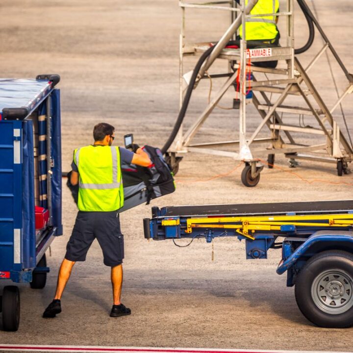baggage handler loading bag on to conveyor belt for plane - Travel Off Path