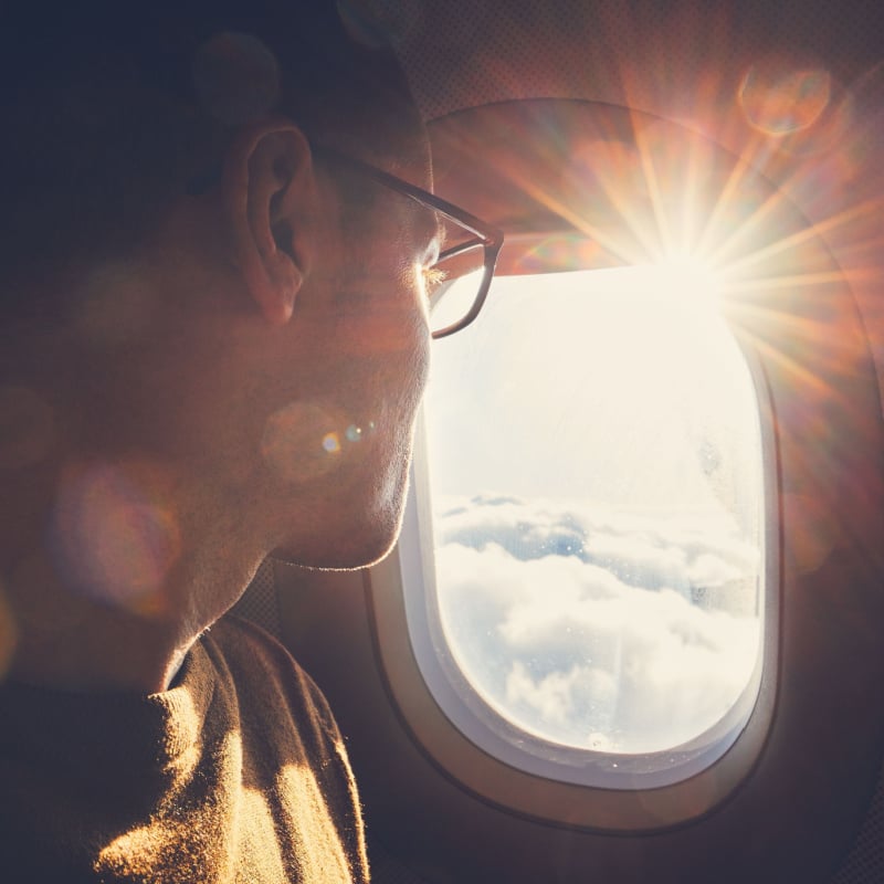 Man looking out airplane window - Travel Off Path