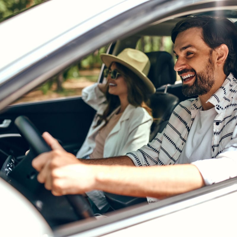 Young couple in a new car. A man driving a car with his girlfriend and ...
